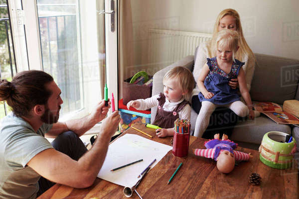 Family sitting at table and drawing pictures together - Royalty-free ...