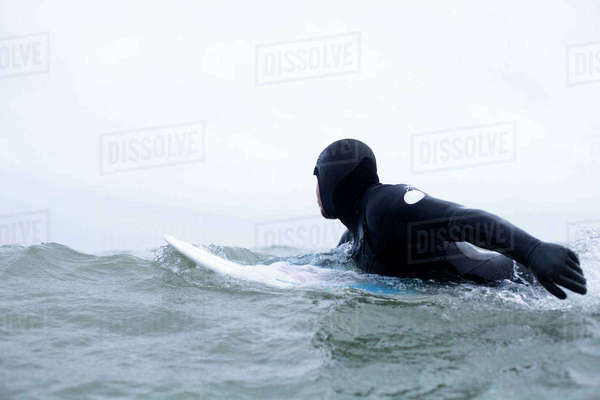 Surfer wearing wetsuit floating with board in wintery sea - Stock Photo ...