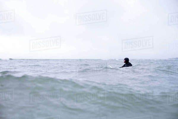 Surfer wearing wetsuit floating with board in wintery sea - Stock Photo ...