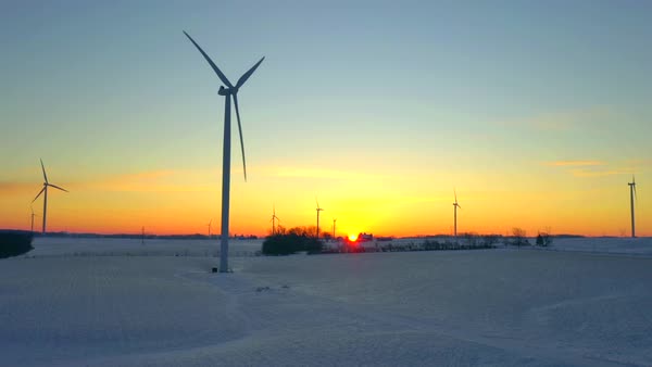 Giant wind Turbines silhouetted against colorful twilight sky, moving ...