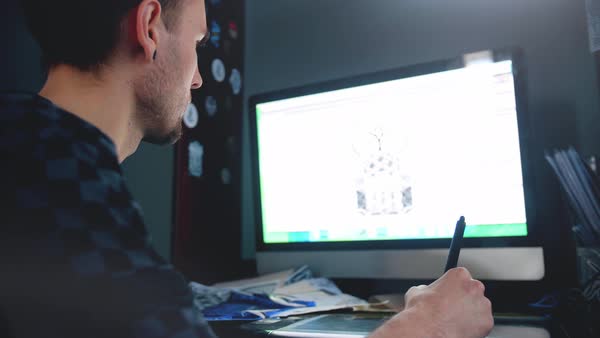 Male tattoo artist designing tattoo on a computer screen with a digital ...