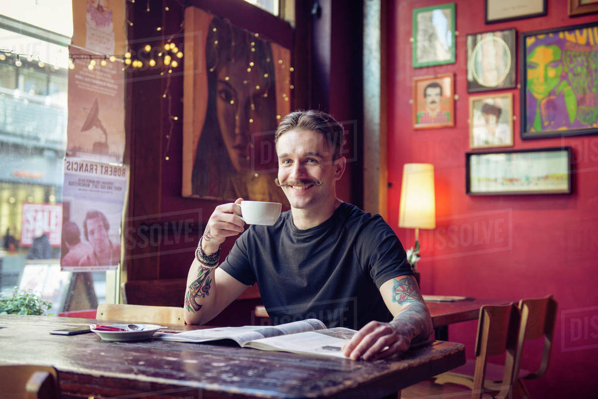 A young man sitting at a table in a coffee shop in Manchester - Royalty ...