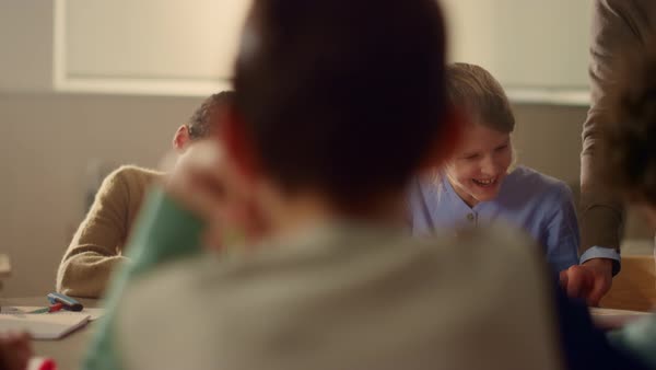 Children learning at round table in classroom. Pupils doing class work ...