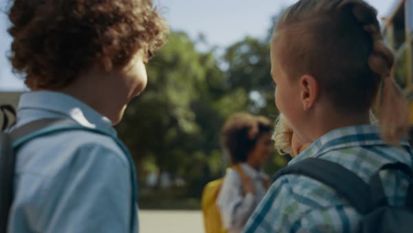 Elementary age boys talking joking at school bus. Teen friends ...