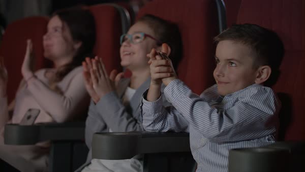 Satisfied children applauding in cinema. Storm of applause in cinema ...