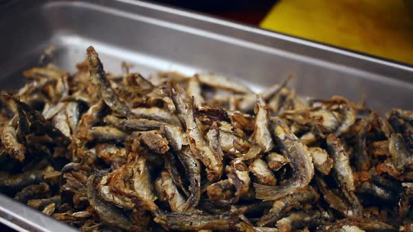 Small fried fish in a metal tray, delicious street food on food market ...