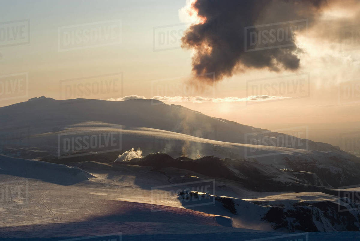 Plume of ash from Eyjafjallajokull volcano, silhouetted against sunset ...