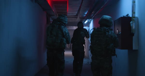 Back view of anonymous SWAT team with laser sights walking in dark ...