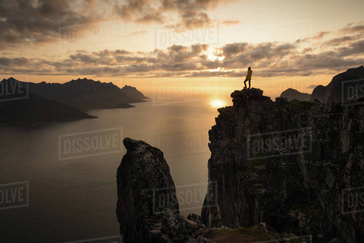 Woman standing on rock against cloudy sky during sunset - Royalty-free ...