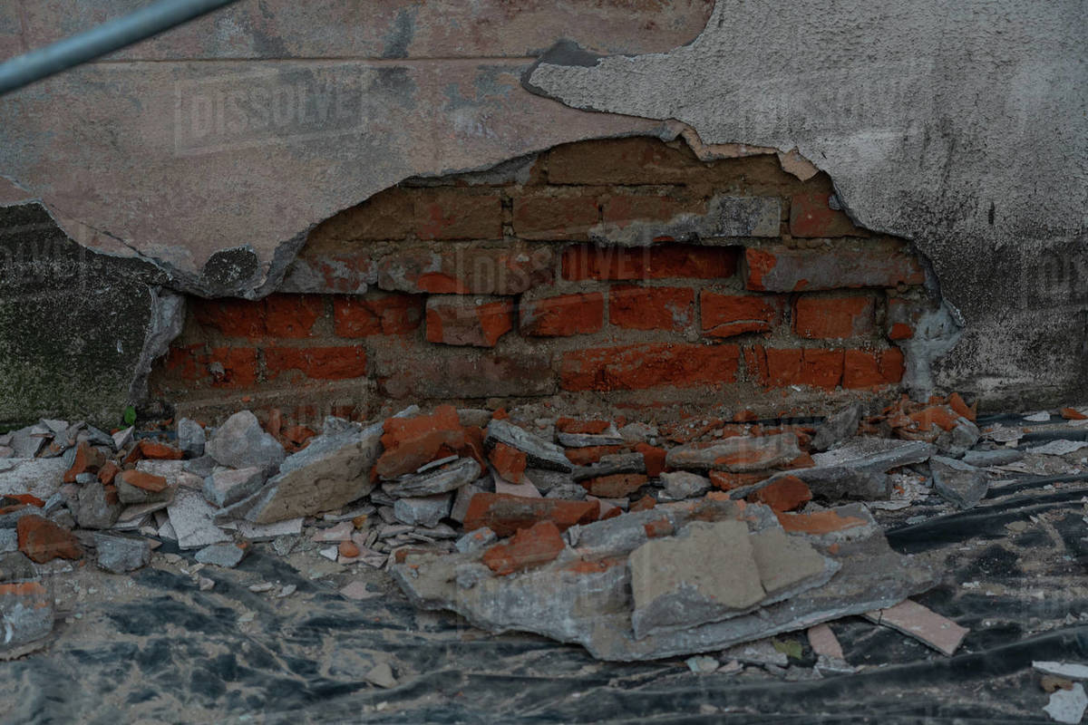 Old, fallen-off plaster from a brick building. Red brick behind the ...