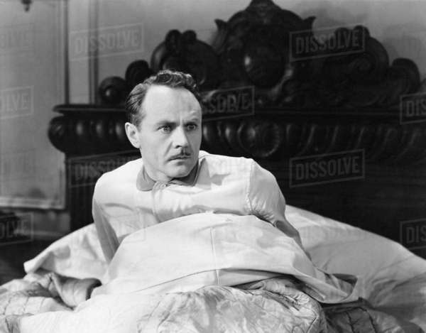 Startled man sitting up in bed - Royalty-free Stock Photo | Dissolve