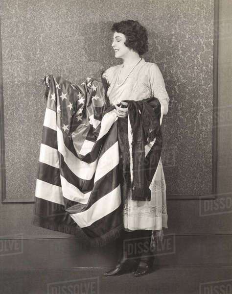 Woman with draped American flag over her arms - Stock Photo - Dissolve