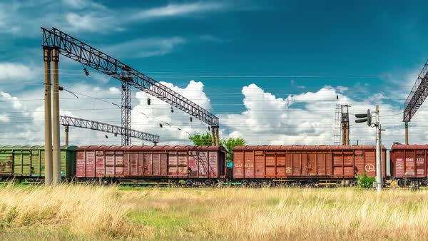 A chain of cargo wagons on a rail road at the background blue sky ...