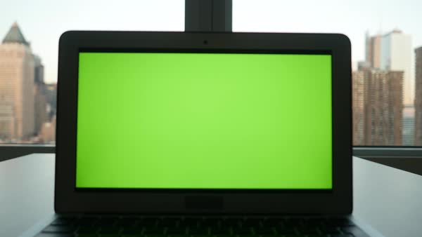 Laptop computer screen in high-rise tower office with green screen ...