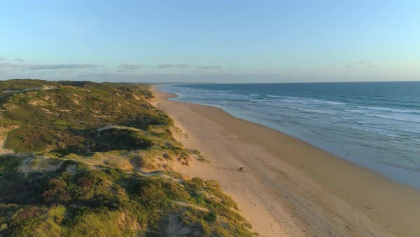 Aerial cinematic rise over long stretch of ocean beach revealing scenic ...