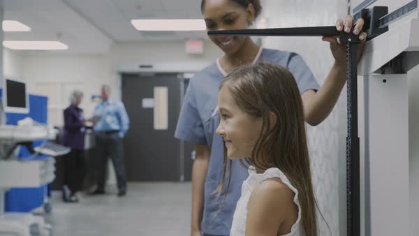 Medium shot of a nurse measuring height of a girl in hospital - 4K ...