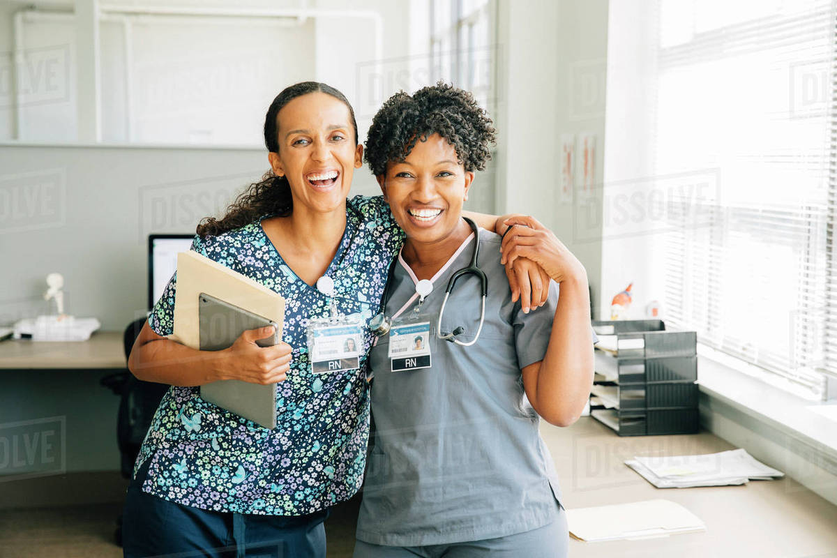 Portrait of smiling nurses hugging near window - Royalty-free Stock ...