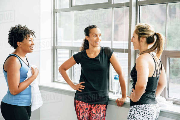 Friends relaxing near window after workout - Royalty-free Stock Photo ...
