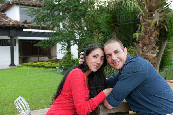 Affectionate Hispanic couple sitting outdoors - Stock Photo - Dissolve