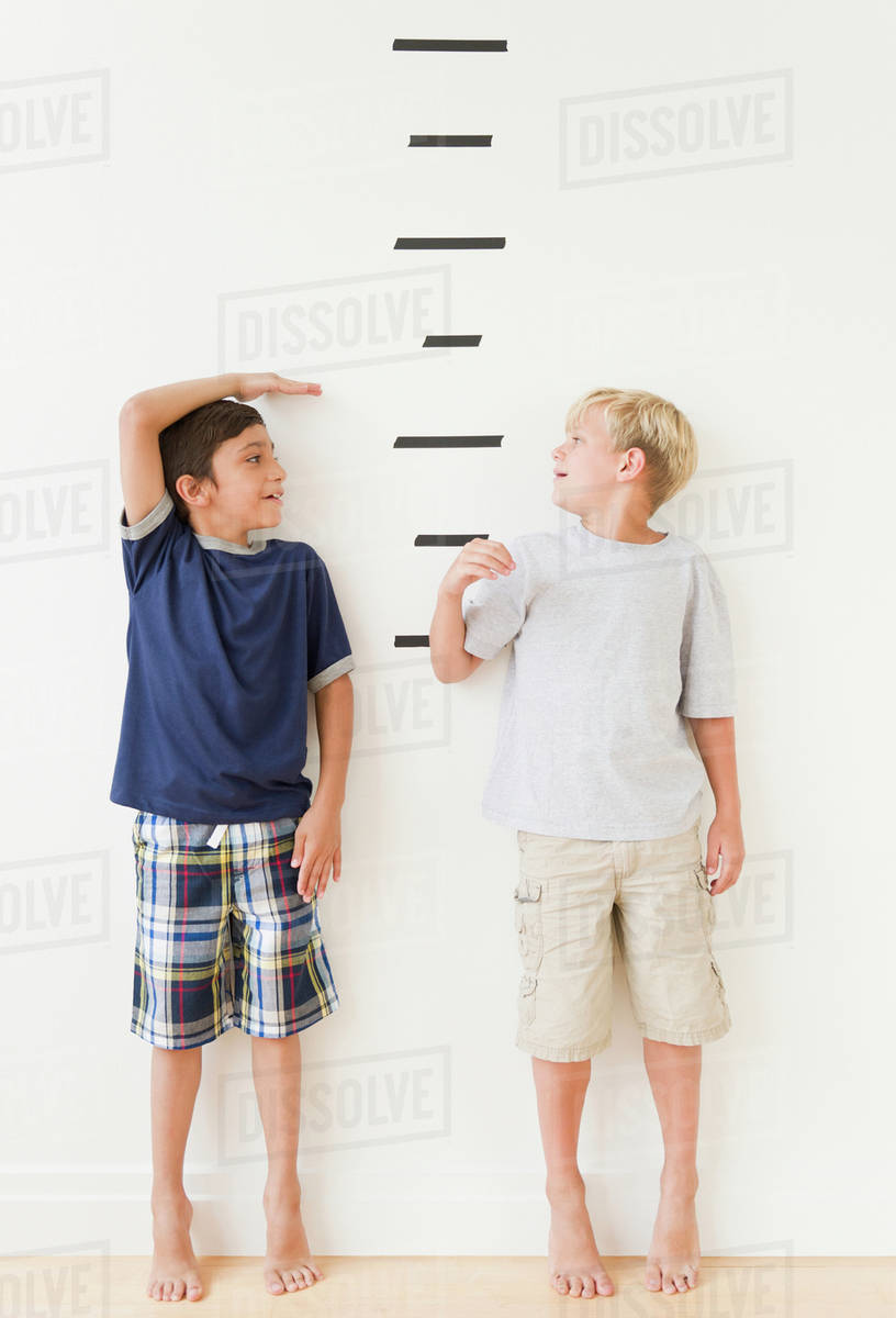 Boys measuring themselves against marks on wall - Royalty-free Stock ...