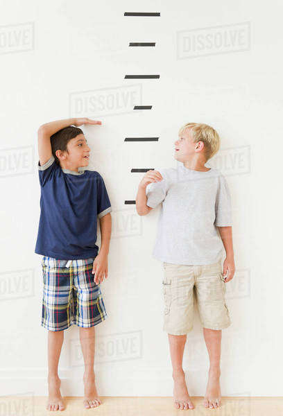 Boys measuring themselves against marks on wall - Royalty-free Stock ...