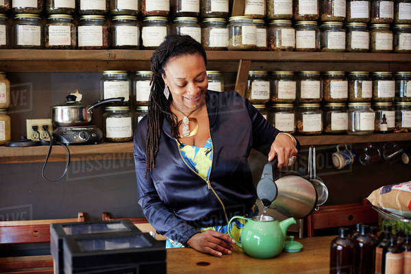 Black woman pouring tea in tea shop - Royalty-free Stock Photo | Dissolve