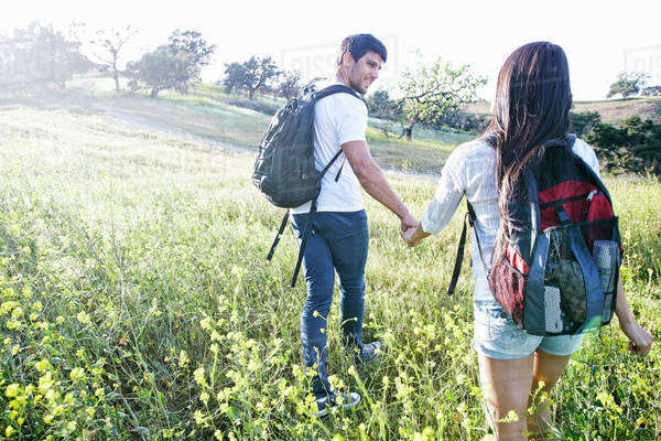 Couple carrying backpacks in field - Royalty-free Stock Photo | Dissolve