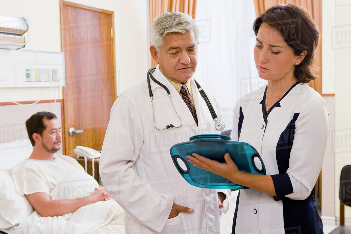 Doctor and nurse discussing patient in hospital room - Royalty-free ...