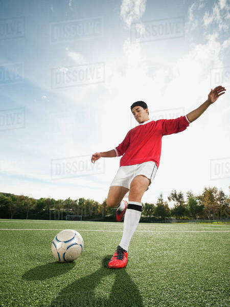 Mixed race soccer player kicking soccer ball - Royalty-free Stock Photo ...