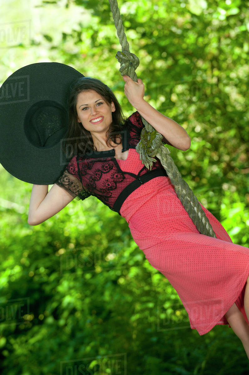 Smiling Caucasian woman swinging on rope swing - Stock Photo - Dissolve