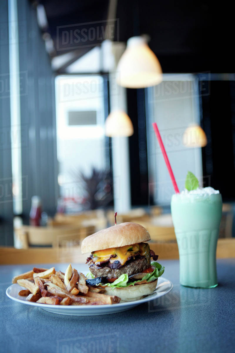 Cheeseburger, french fries and milkshake in diner - Stock Photo - Dissolve