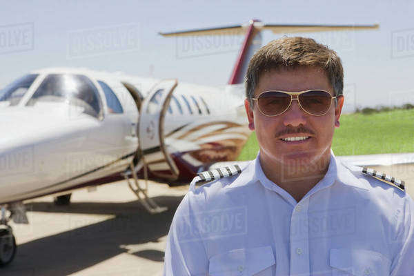 Hispanic pilot standing outside private jet - Stock Photo - Dissolve