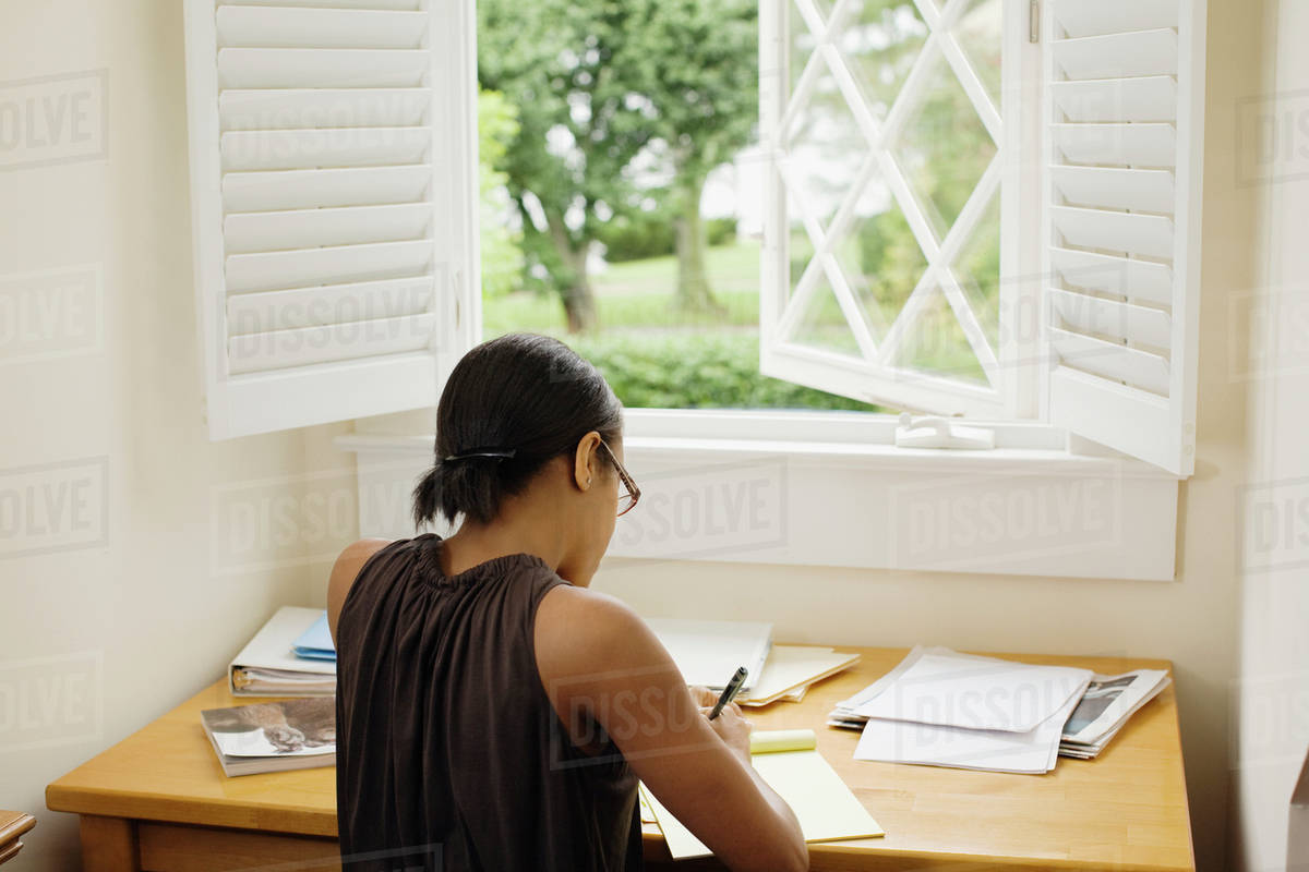 African woman writing at desk - Royalty-free Stock Photo | Dissolve