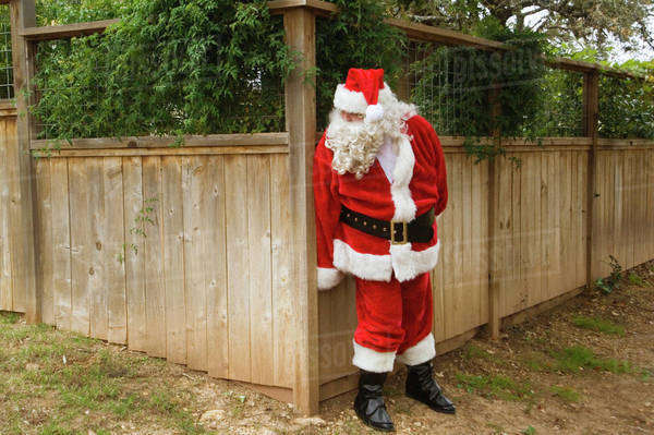 Santa hiding behind fence - Stock Photo - Dissolve