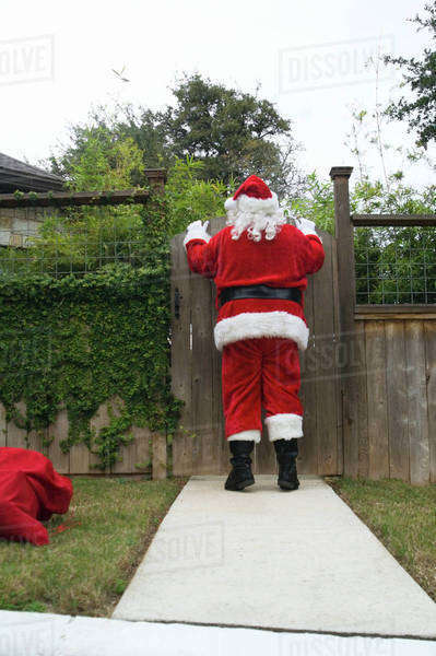Santa peering over fence gate - Stock Photo - Dissolve