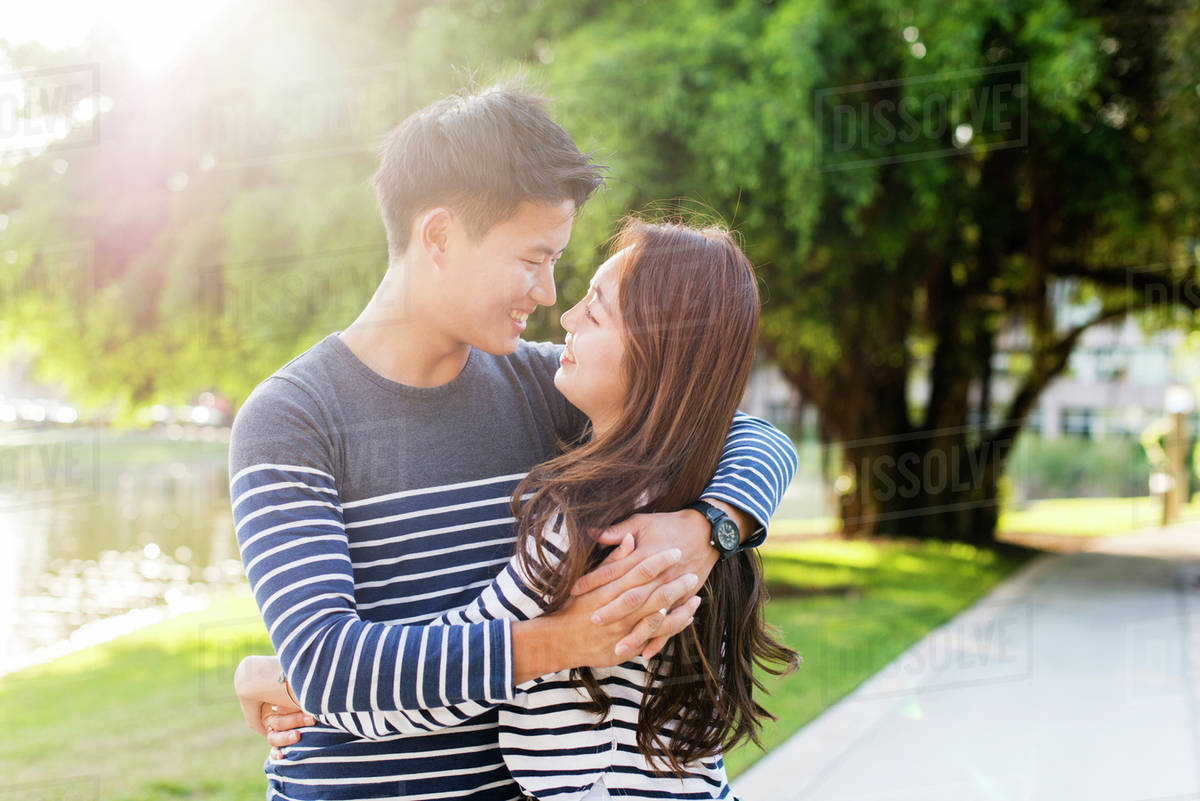 Smiling Korean couple hugging in park - Royalty-free Stock Photo | Dissolve