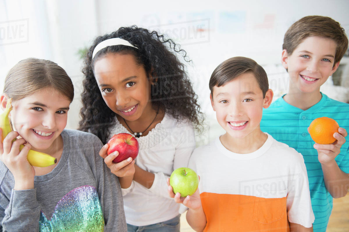 Smiling children playing with healthy fruit - Stock Photo - Dissolve