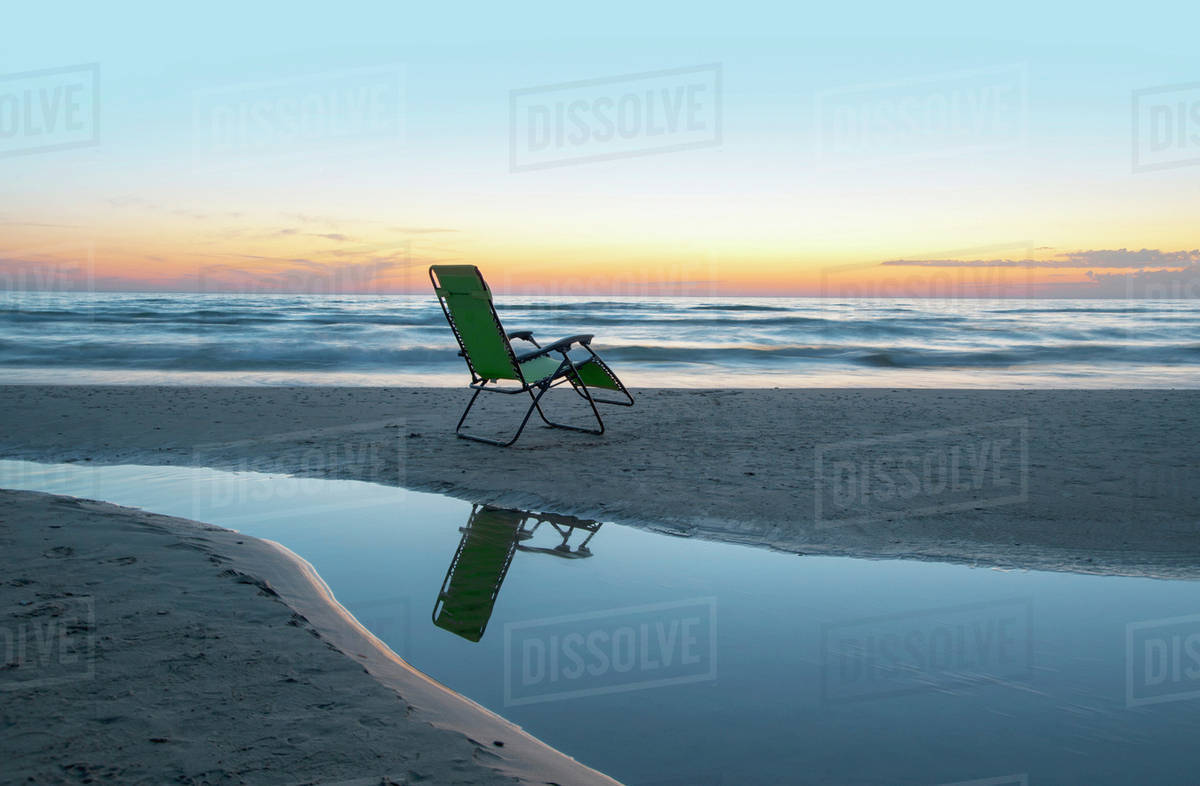 Lounge chair on beach at sunset - Royalty-free Stock Photo | Dissolve