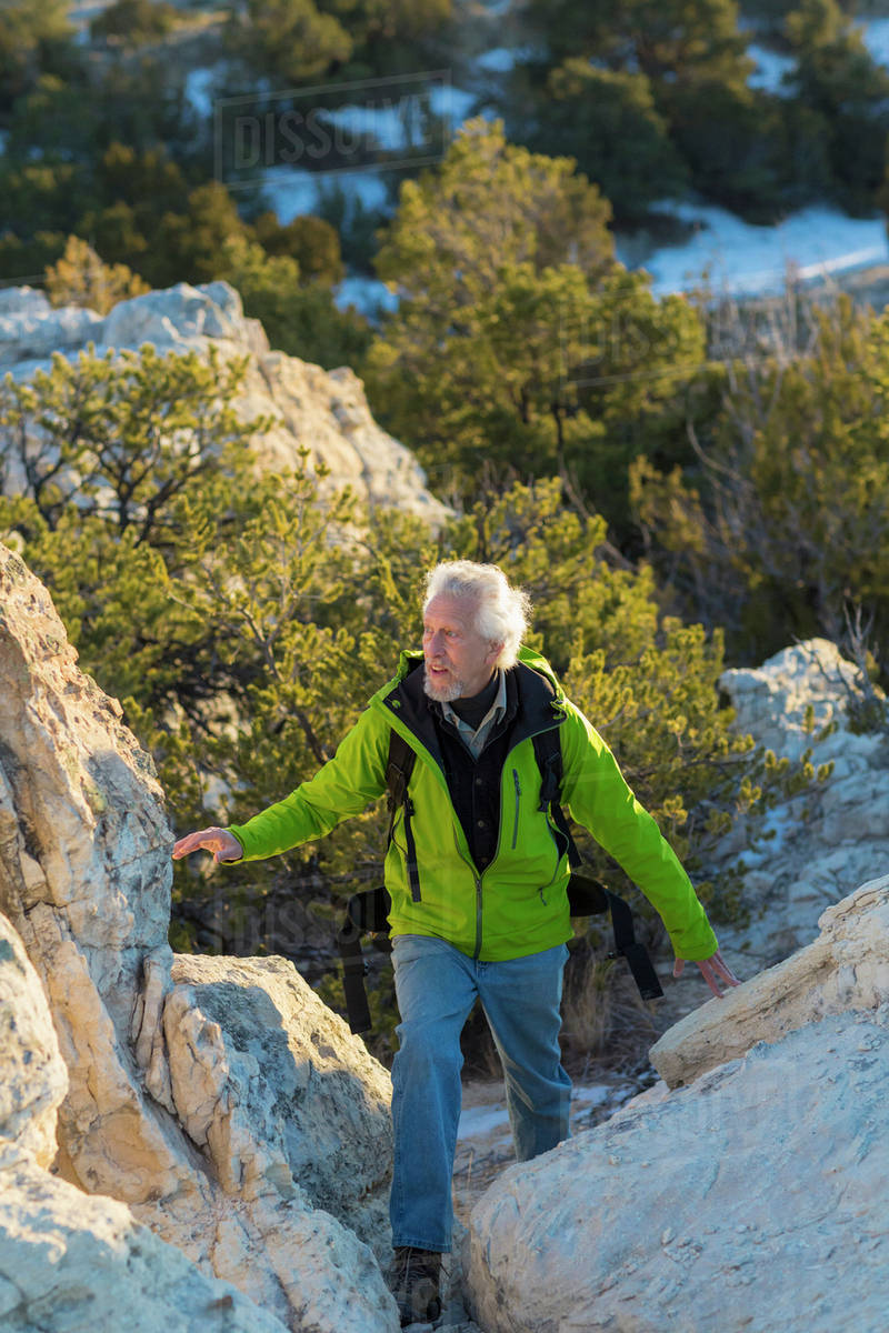 Older man climbing remote rock formations - Stock Photo - Dissolve