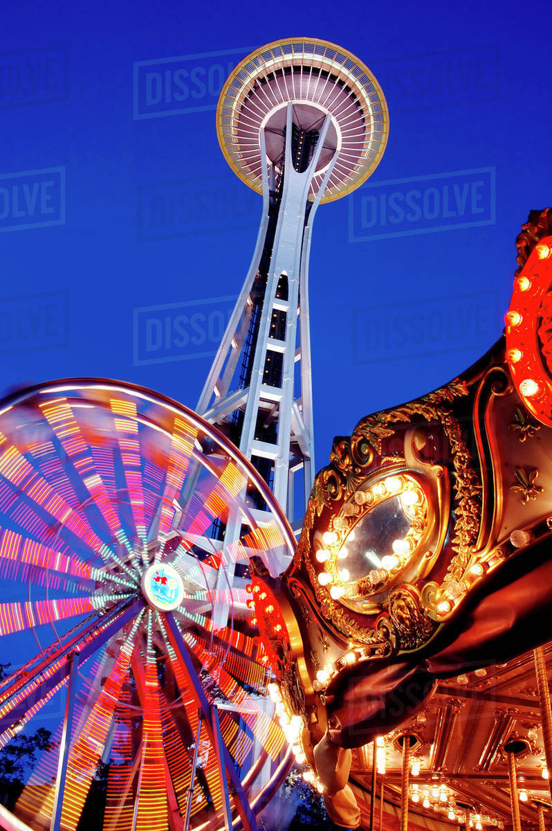 Low angle view of Space Needle, ferris wheel and carousel under night ...