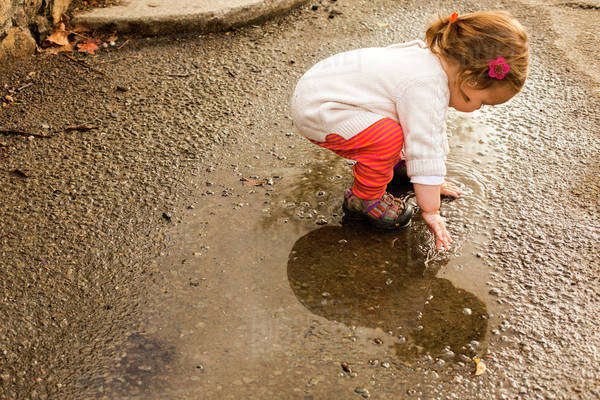 Caucasian baby girl playing in puddle - Stock Photo - Dissolve
