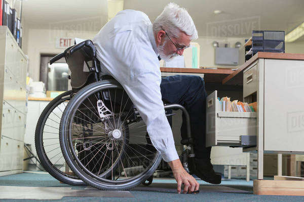 Caucasian businessman picking up object on floor - Stock Photo - Dissolve