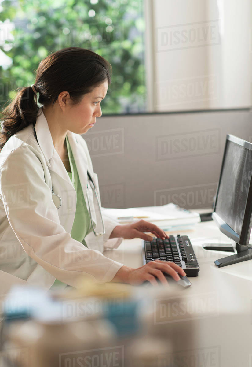 Mixed race doctor working on computer in hospital - Stock Photo - Dissolve