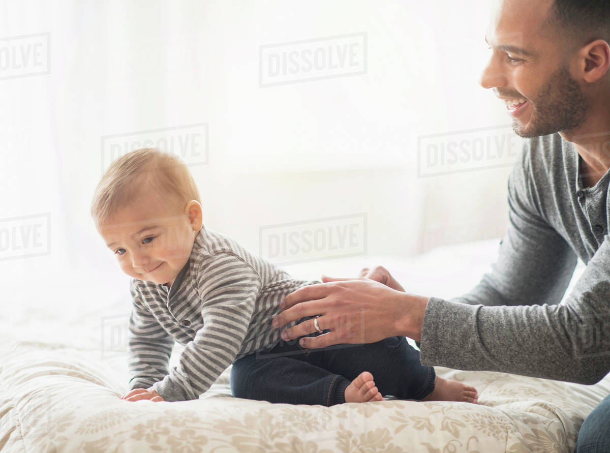 Father playing with baby son on bed - Royalty-free Stock Photo | Dissolve