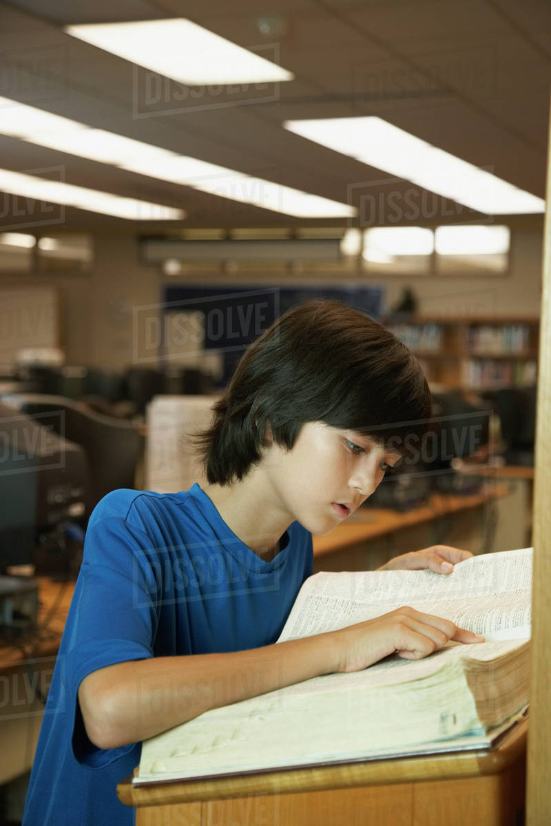 Asian boy reading library dictionary - Stock Photo - Dissolve