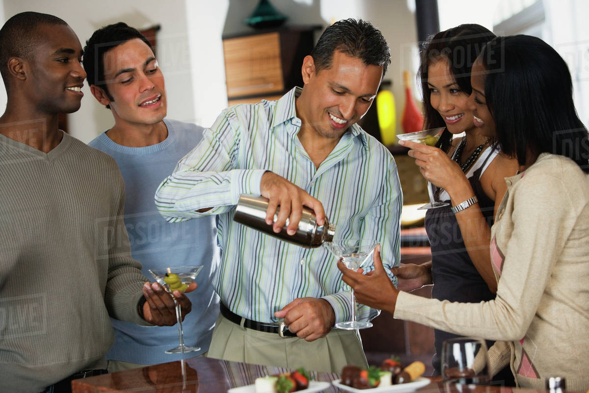 Hispanic man pouring drink at party - Royalty-free Stock Photo | Dissolve