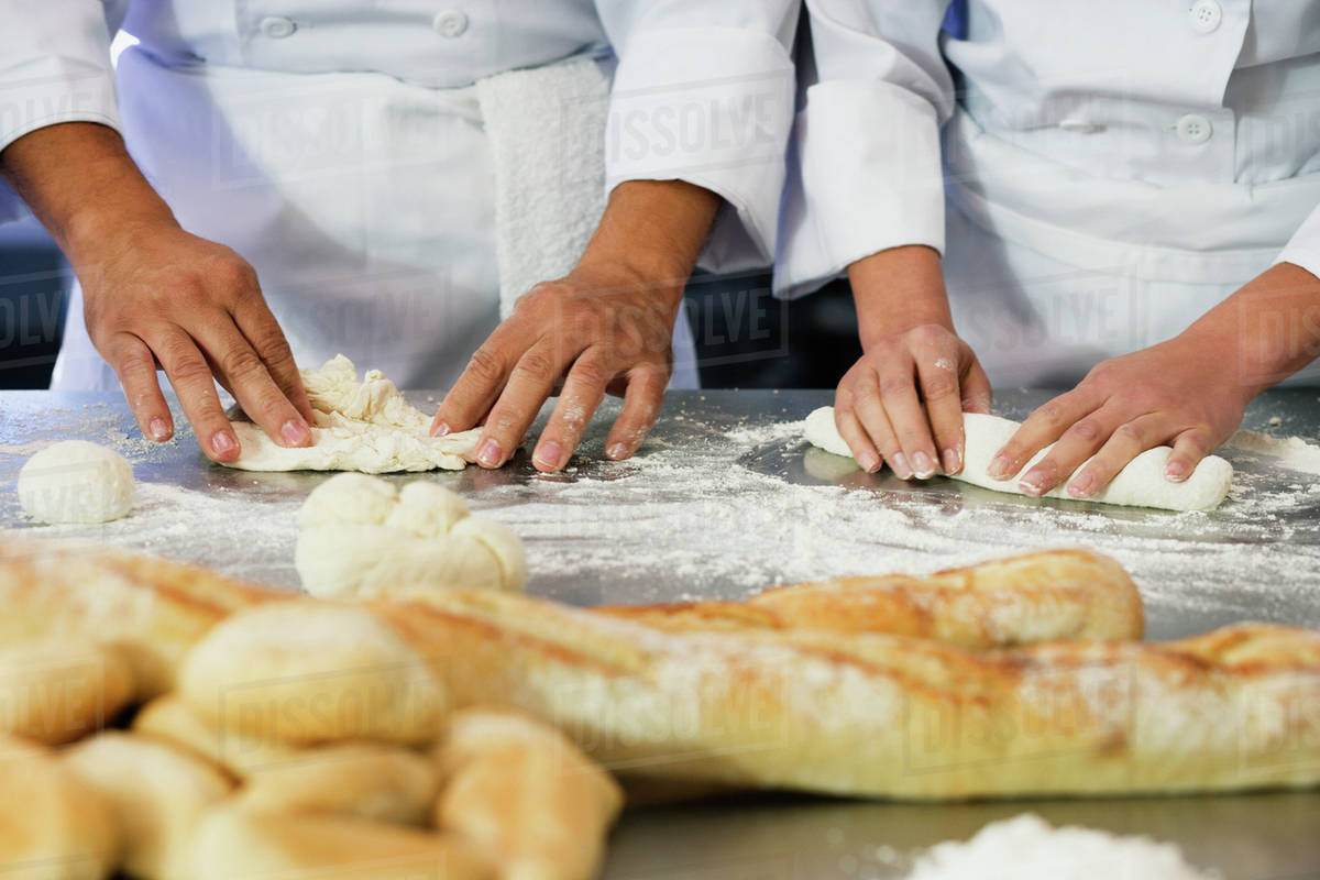 Close up of bakers rolling dough - Royalty-free Stock Photo | Dissolve