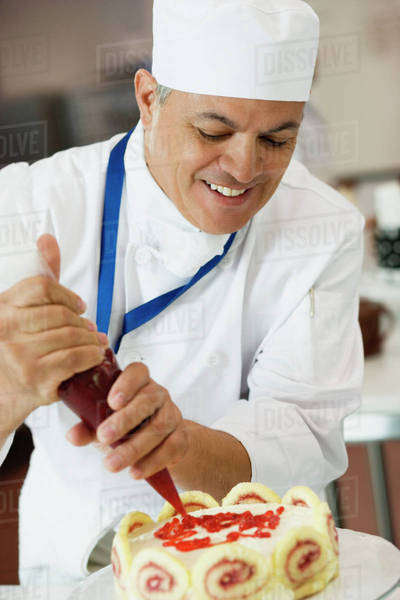 Hispanic male pastry chef decorating cake - Royalty-free Stock Photo ...