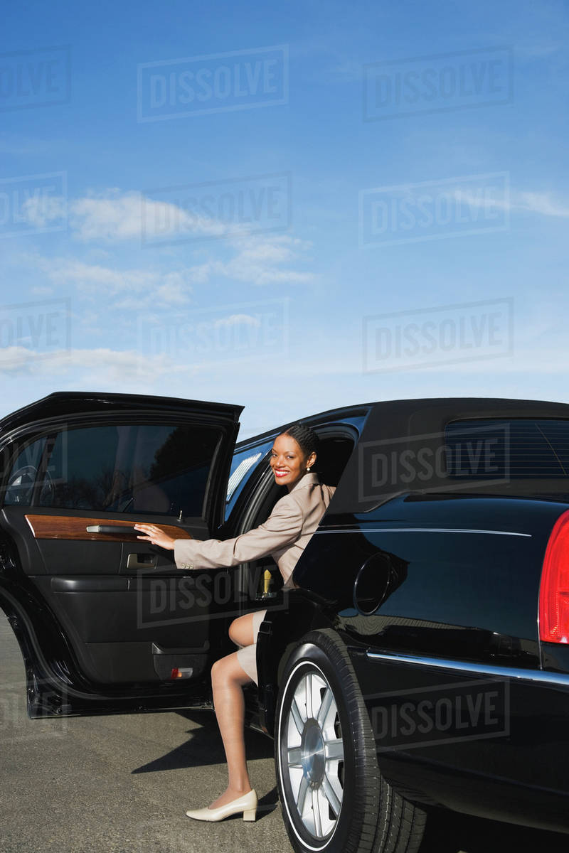 African businesswoman getting out of limousine - Stock Photo - Dissolve