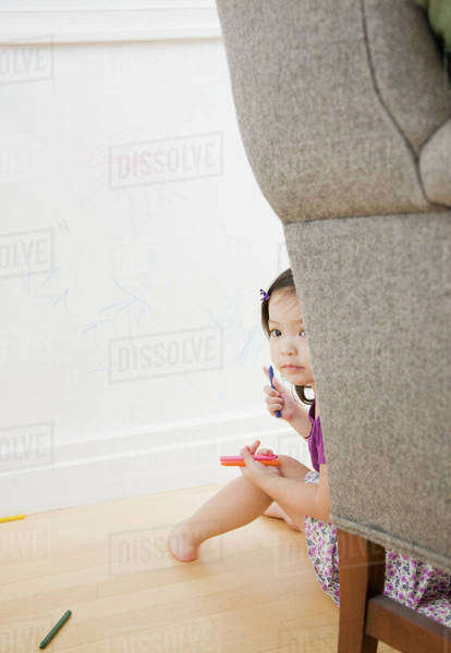 Toddler girl hiding behind chair - Royalty-free Stock Photo | Dissolve